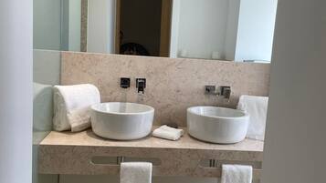Um banheiro moderno com duas pias grandes brancas, um espelho e um porta-toalhas.