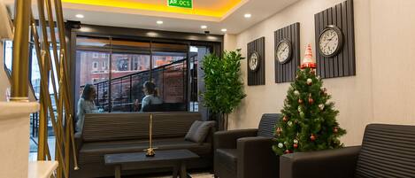Um hall com balcão de recepção, área de estar e árvore de Natal.