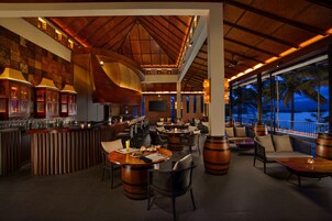 Um restaurante com área de bar, mesas ao ar livre e vista para o mar.
