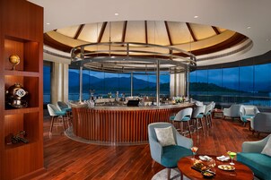 Uma área de bar com balcão circular, assentos e vista para as montanhas.