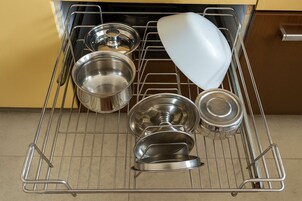 Uma cozinha com um escorredor de metal contendo diversas panelas e frigideiras de aço inoxidável.