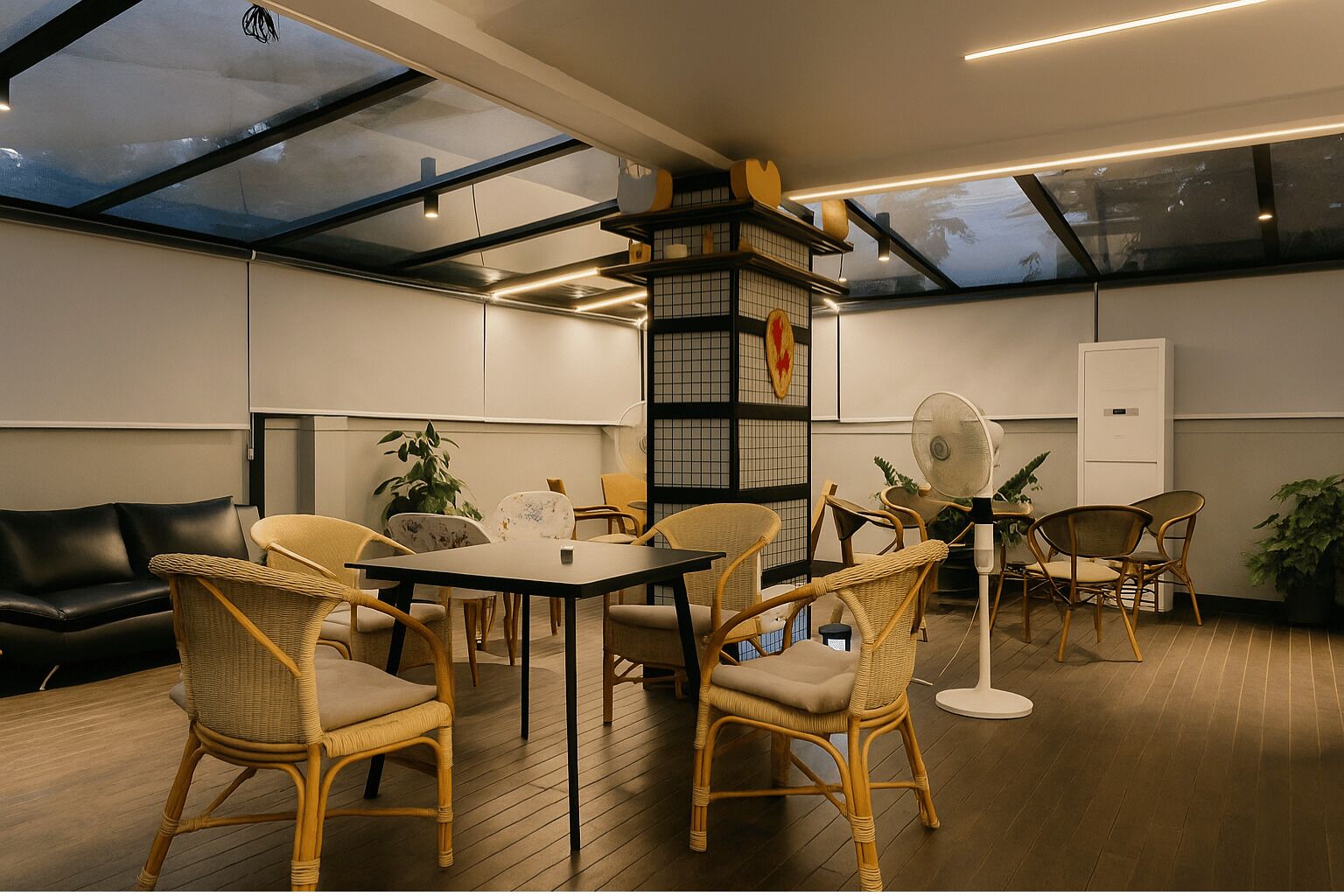 Uma sala de reunião moderna com teto de vidro, cadeiras de vime, uma mesa preta e um quadro branco.