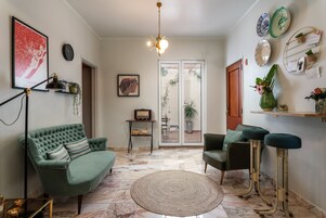 Sala de estar com um sofá verde, um tapete redondo e uma luminária no teto.