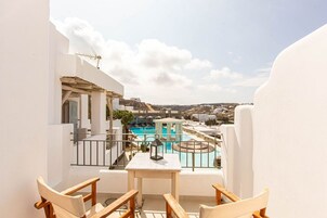 Varanda com mesa e cadeiras dando vista para uma piscina e edifícios.