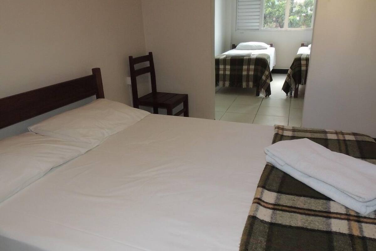Quarto com uma cama grande, uma cadeira e uma pequena mesa com toalha.
