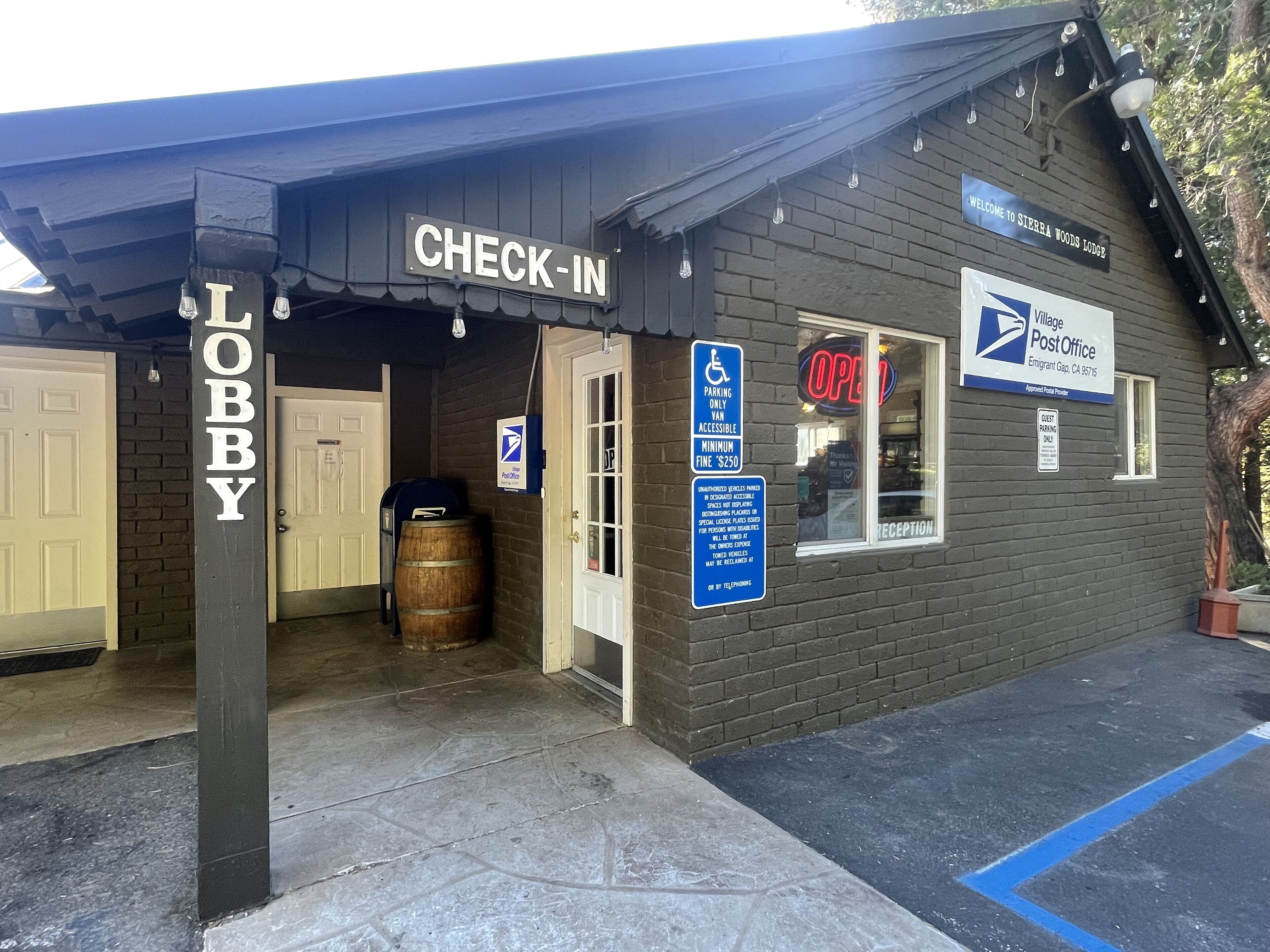 Uma pousada com placas indicando 'CHECK-IN', 'LOBBY', 'ESCRITÓRIO DE CORREIO' e 'ESCRITÓRIO DE CORREIO DA VILA'.
