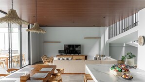 Uma cozinha moderna com bancada de mármore, cadeiras de madeira e uma mesa de jantar posta para seis.
