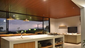 Cozinha moderna com uma ilha grande, armários de madeira e vista para a cidade.
