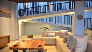 Um interior moderno com mesa de centro de madeira, sofá bege e varanda com grades de metal.