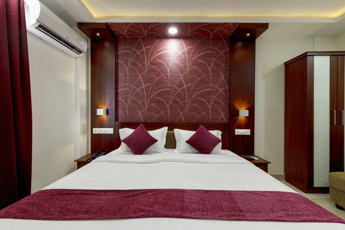 Quarto de hotel com uma cama grande, duas mesas de cabeceira, um guarda-roupa e ar condicionado fixado na parede.