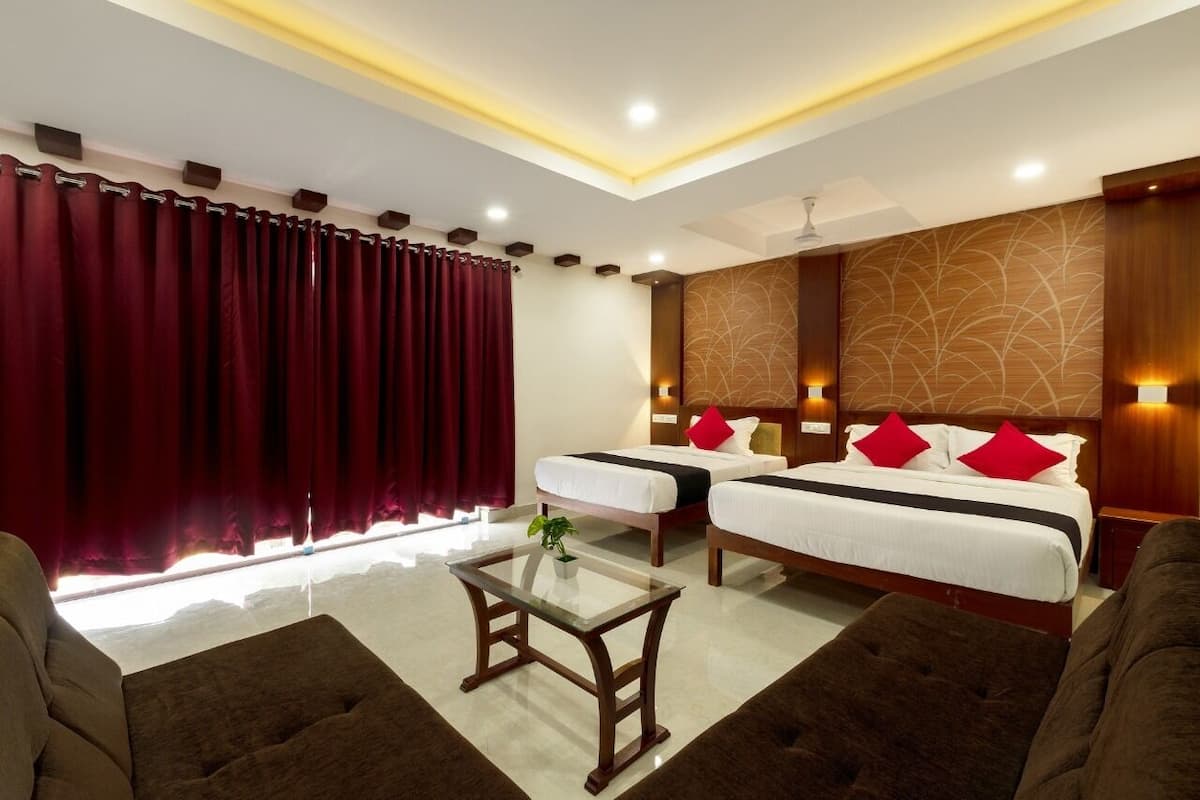 Quarto de hotel com duas camas, uma mesa de centro de vidro e vista para a cidade.