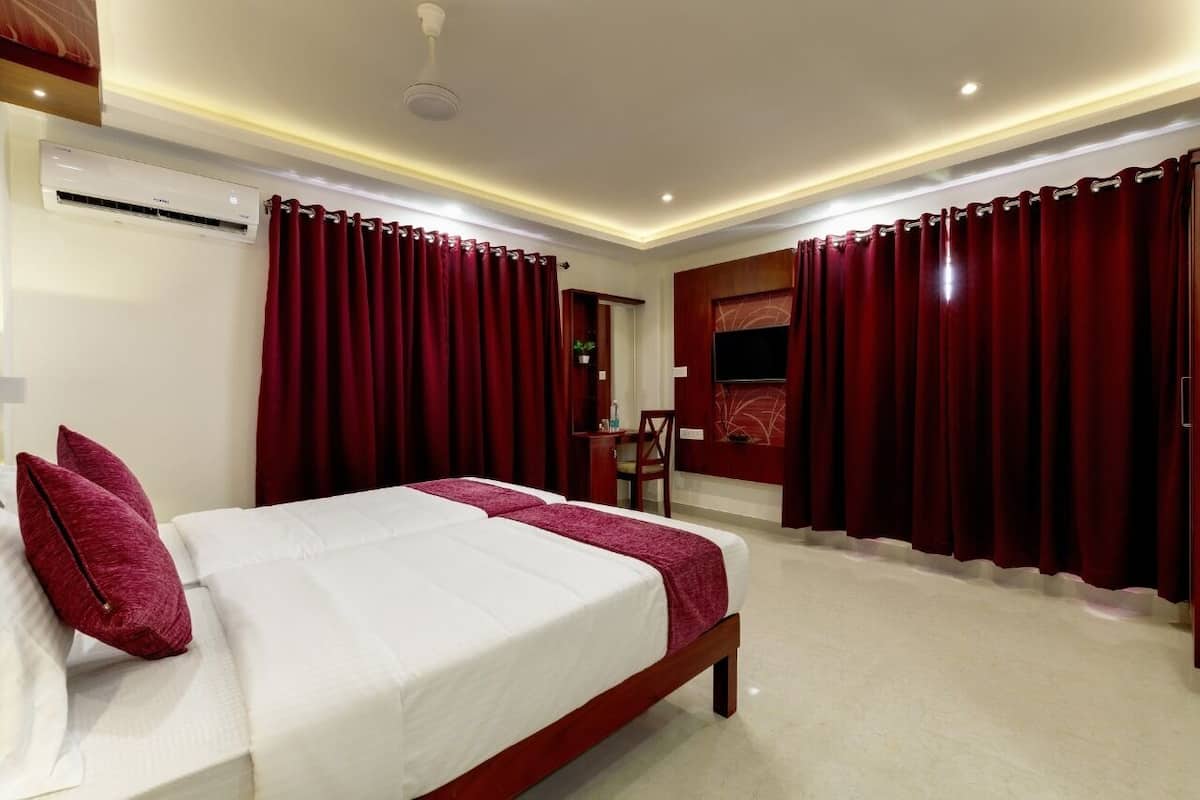 Quarto de hotel com uma cama, cortinas vermelhas, televisão e ar condicionado.