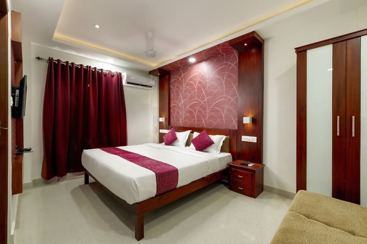 Quarto com cama, mesa de cabeceira, guarda-roupa e televisão.
