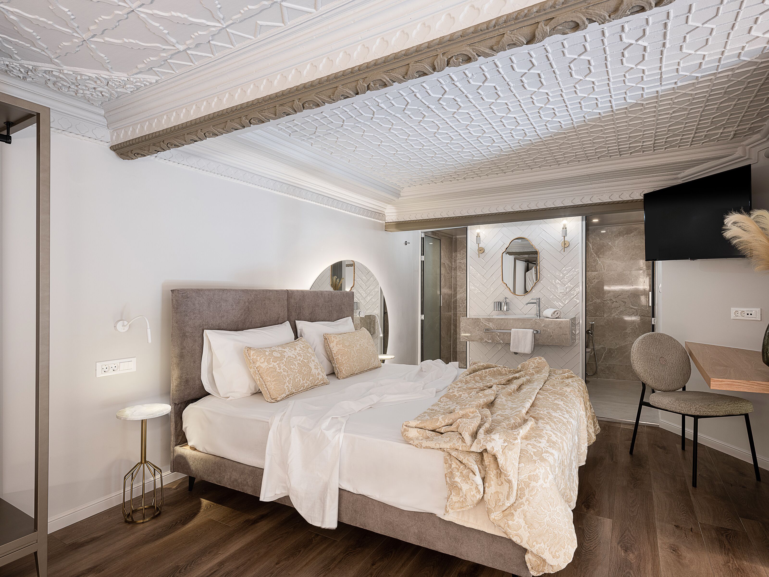Quarto moderno com uma cama grande, uma penteadeira com espelho e uma área de chuveiro.