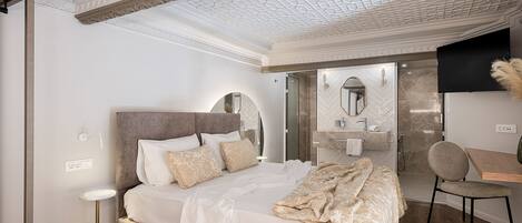 Quarto moderno com uma cama grande, uma penteadeira com espelho e uma área de chuveiro.