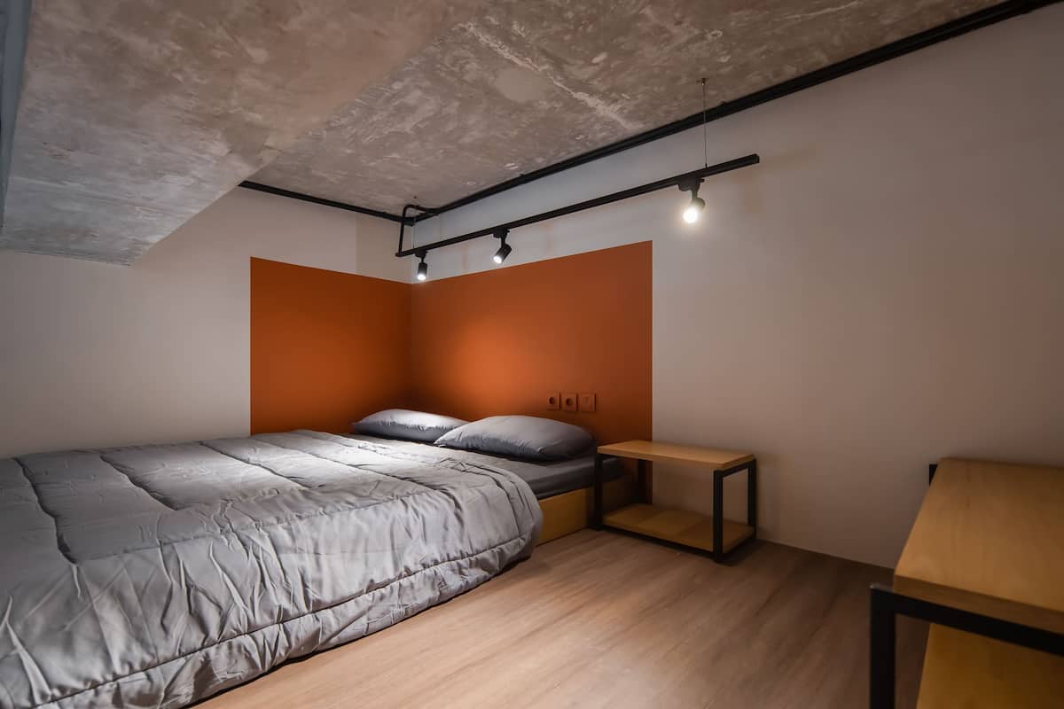 Quarto com uma cama, mesa de cabeceira e escrivaninha.