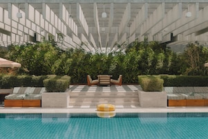 Área de piscina com vista desobstruída da água, cercada por vegetação e áreas de estar.