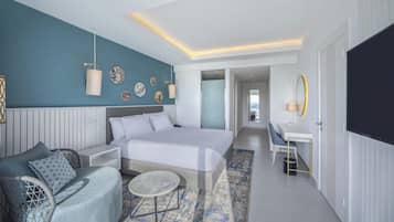 Quarto de hotel moderno com cama, área de estar, escrivaninha e televisão.