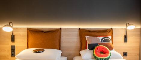 Quarto de hotel com duas camas, cada uma com roupa de cama branca e um design de almofada exclusivo.