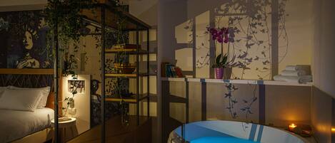 Uma casa de banho moderna com banheira, prateleiras com plantas, um espelho e uma parede com padrões florais.