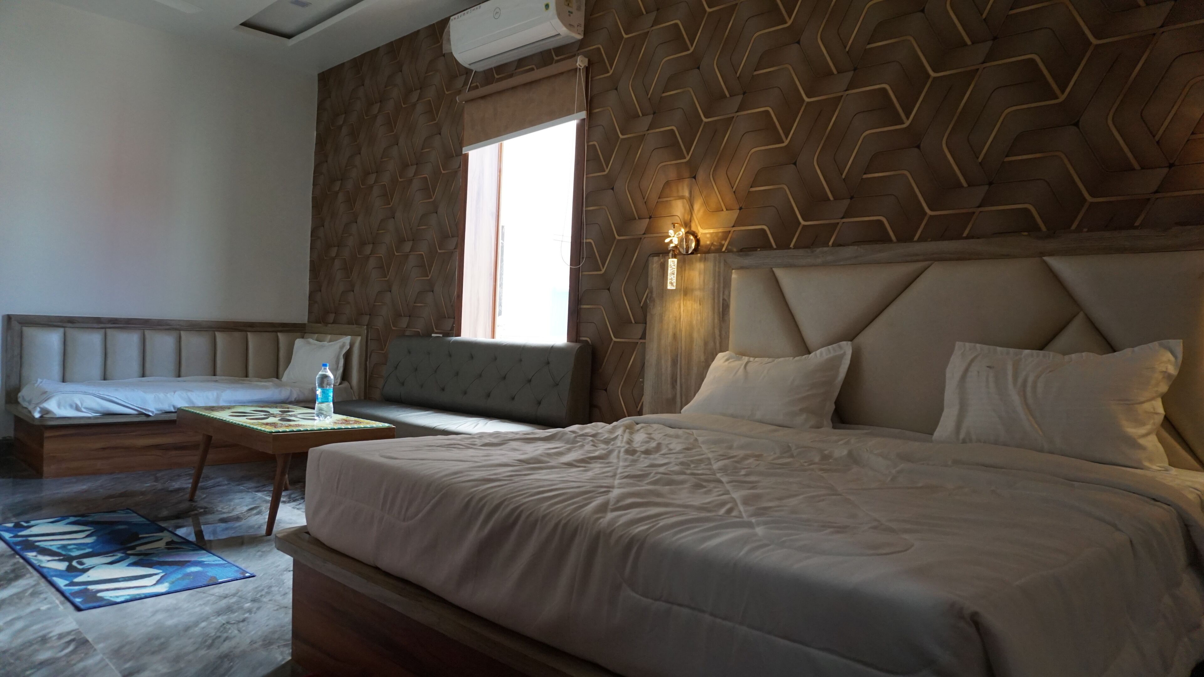 Quarto de hotel com uma cama grande, um sofá, uma mesinha e uma janela.
