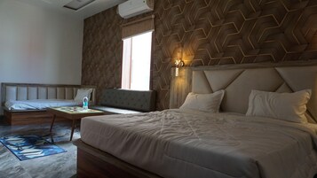 Quarto de hotel com uma cama grande, um sofá, uma mesinha e uma janela.