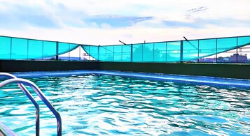 Piscina com escada metálica, rodeada por uma cobertura azul de malha.