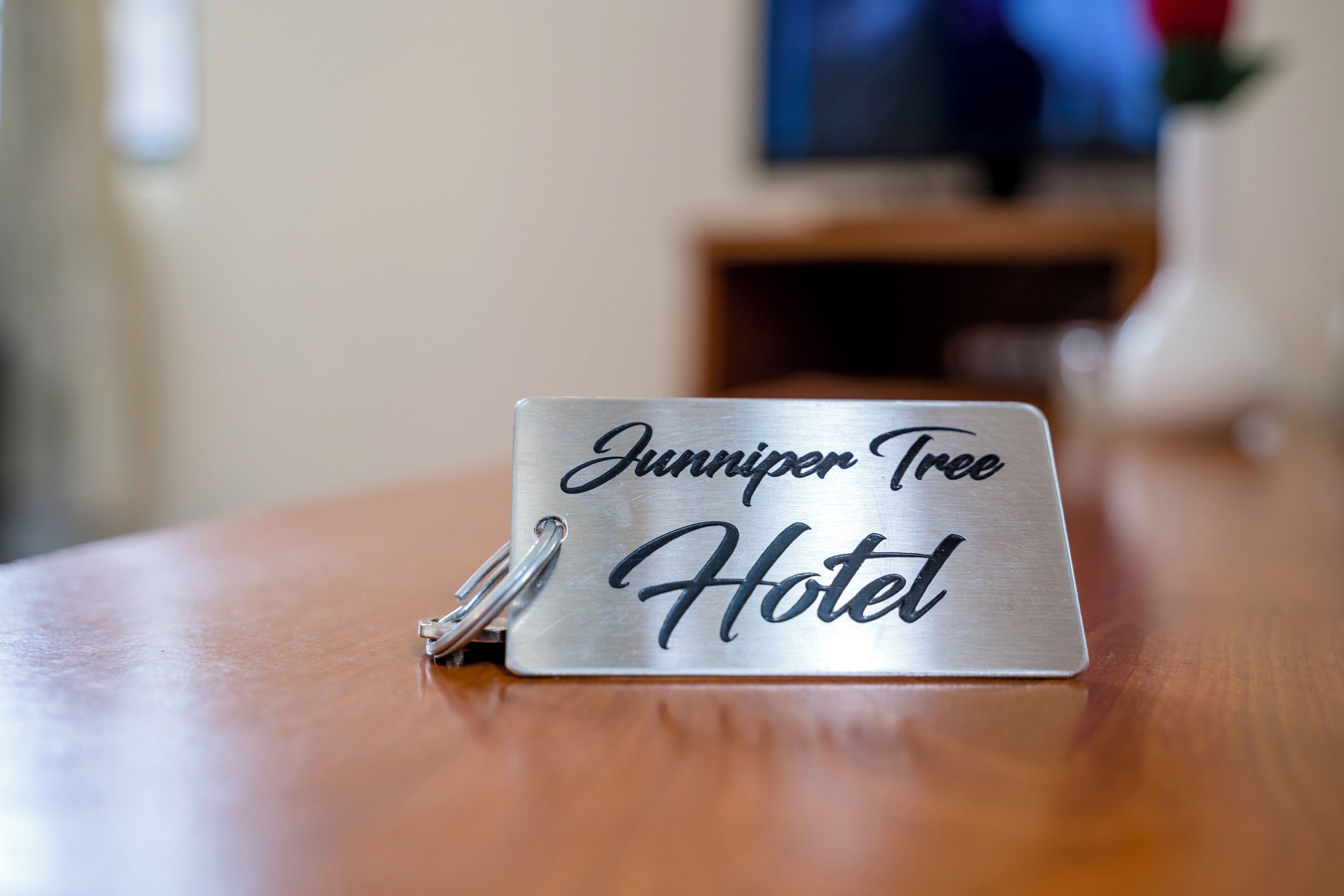 Uma placa de metal com a inscrição 'Jennifer Tree Hotel', apoiada em uma superfície de madeira.