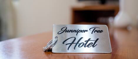 Uma placa de metal com a inscrição 'Jennifer Tree Hotel', apoiada em uma superfície de madeira.