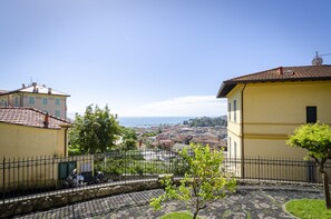 Uma cidade costeira com edifícios amarelos, uma área pavimentada com cerca e vista para o mar.