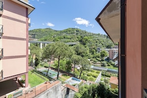 Área residencial com vista para uma colina verde, uma ponte e uma piscina.