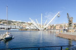 Vista para a frente marítima com uma moderna estrutura de ponte, barcos e um horizonte urbano ao fundo.