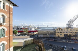 Vista costeira com um porto, um barco vermelho e branco e um edifício com a placa 
