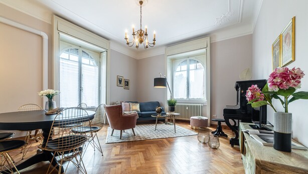 Uma sala de estar ampla, com área de jantar, piano e grandes janelas.