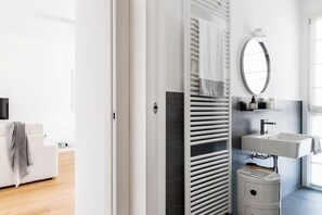 Uma casa de banho moderna com uma pia branca, um espelho e um porta-toalhas.