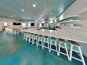Cozinha ampla com uma ilha grande, banquetas e um espaço de jantar com cadeiras.