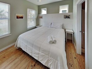 Quarto com uma cama grande, duas mesas de cabeceira, uma cabeceira e uma porta.