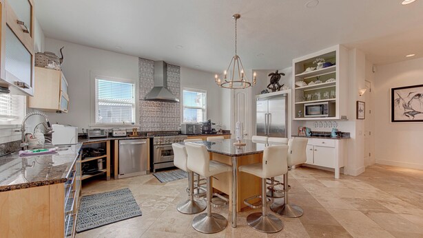 Uma cozinha moderna com ilha central, eletrodomésticos de aço inoxidável e um candelabro.