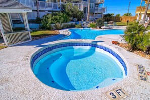 Uma piscina com um aviso de 'Não Mergulhar', rodeada por uma área de deck com espreguiçadeiras e uma pequena cascata.