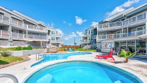 Uma área de piscina com várias piscinas, espreguiçadeiras e um deck de madeira.