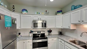 Uma cozinha moderna com armários brancos, eletrodomésticos de aço inoxidável e painel de azulejos.
