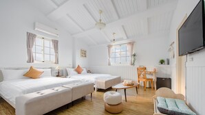 Um quarto espaçoso com uma cama grande, uma cama menor, uma escrivaninha e uma televisão.