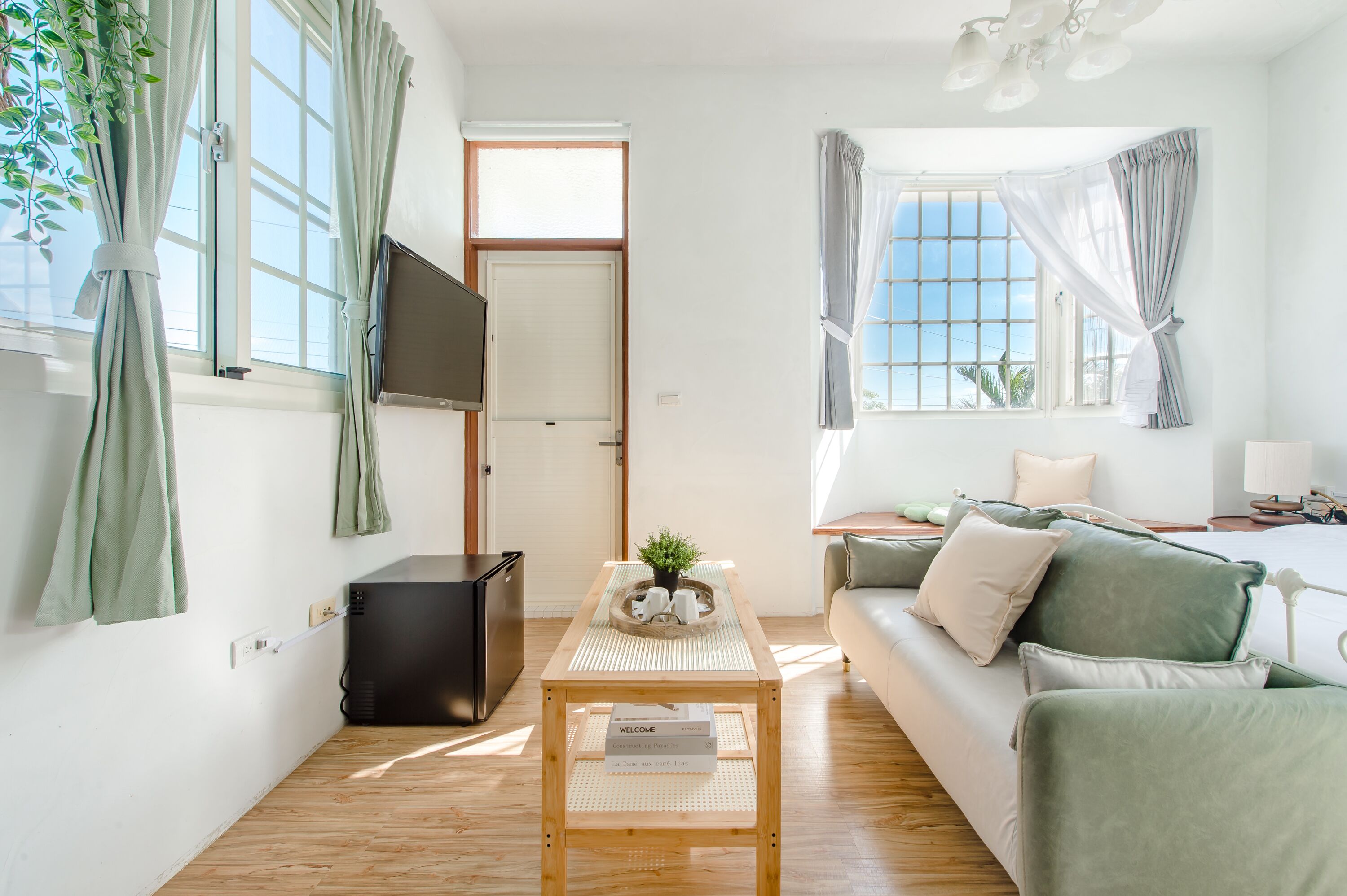 Uma sala de estar moderna com sofá, mesa de centro, televisão e janela com cortinas.