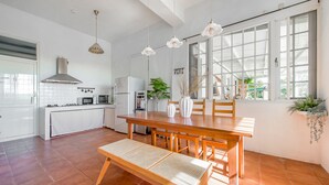 Cozinha moderna com armários brancos, uma mesa de jantar de madeira e um banco.