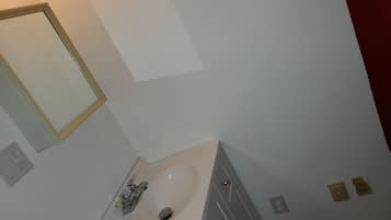 Casa de banho com lavatório, espelho e duas tomadas na parede.