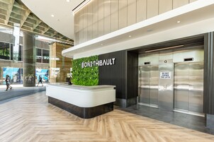 Um saguão de hotel moderno com balcão de recepção, parede verde e elevador.
