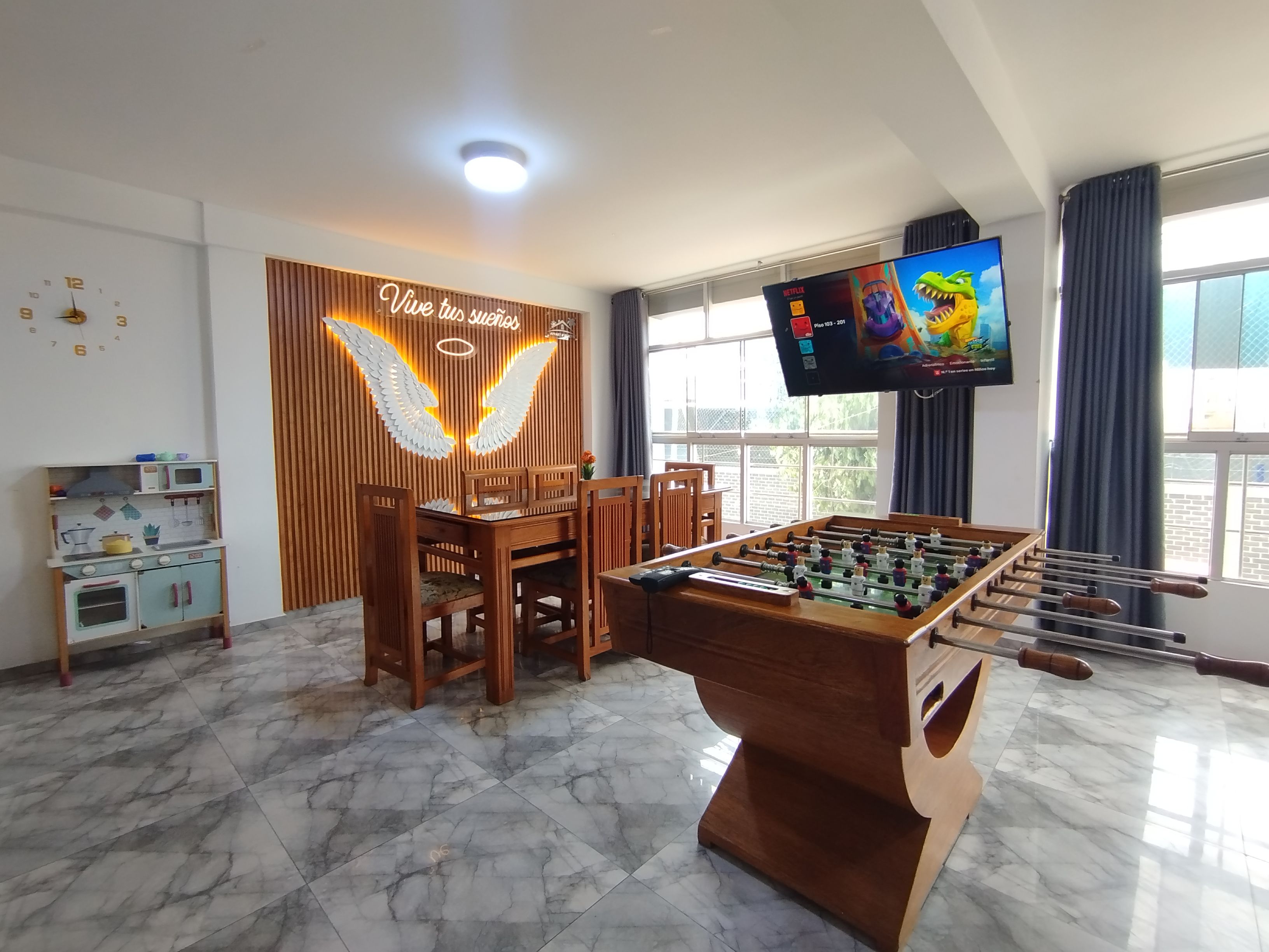 Quarto com mesa de futebol, televisão e painel decorativo na parede.