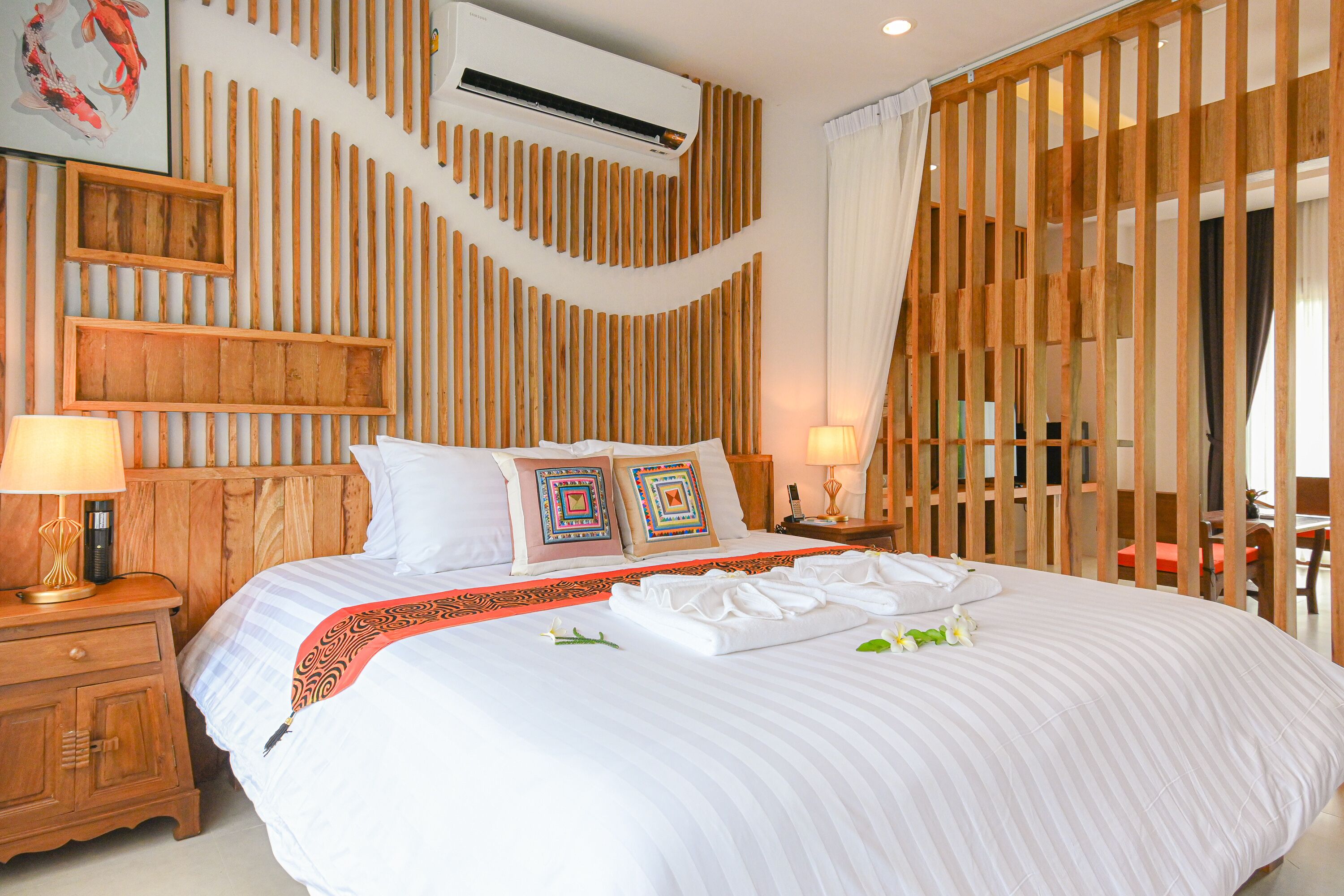 Quarto de hotel com uma cama grande, cabeceira de madeira, mesas de cabeceira com luminárias e um painel decorativo na parede.