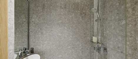 Uma casa de banho moderna com chuveiro de mármore, lavatório com espelho e divisória de vidro.