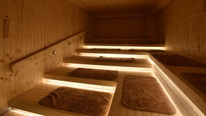 Uma sauna com paredes e bancos de madeira, cada um com uma toalha.
